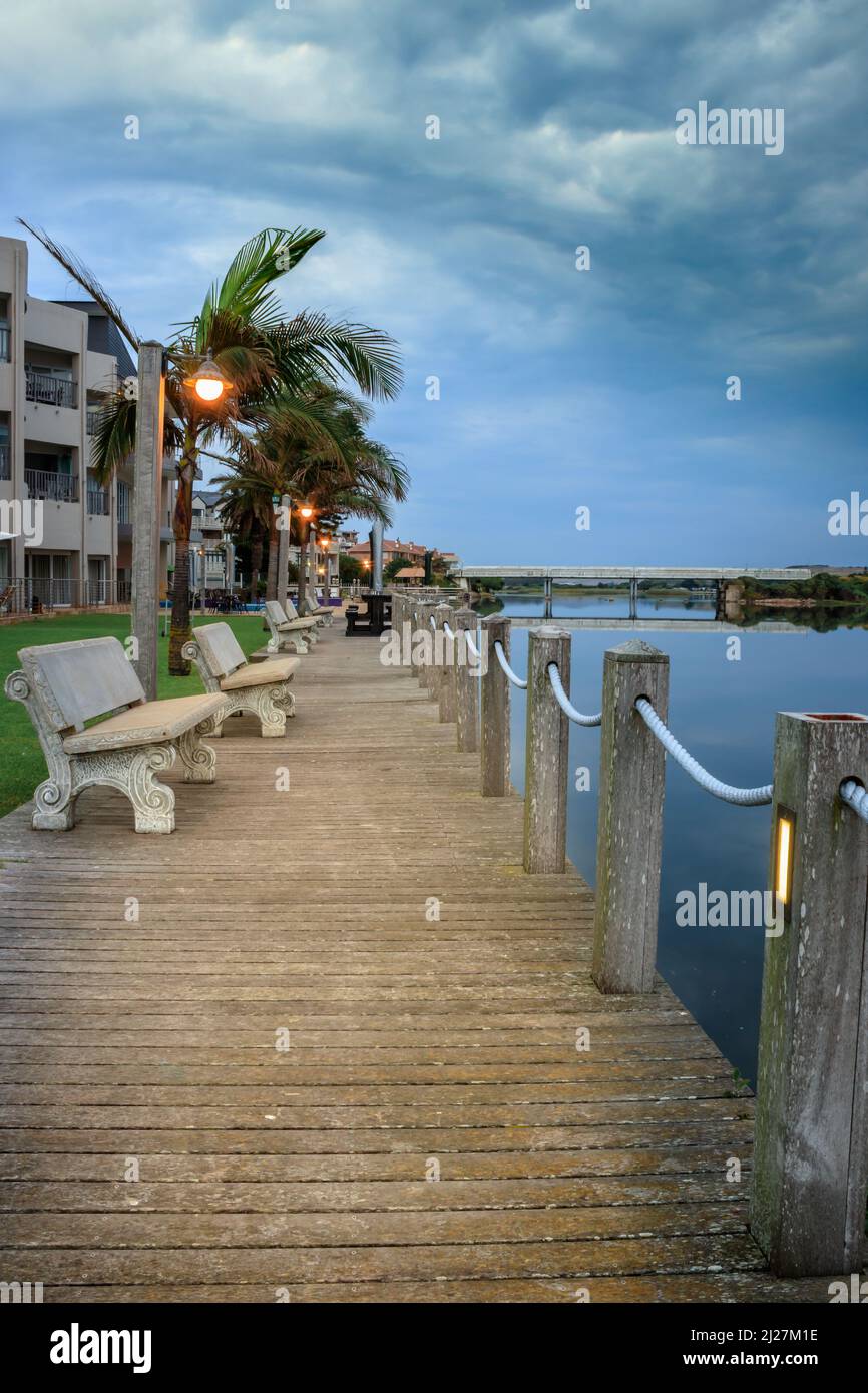 Overcast sunrise over Mossel bay lagoon from a boardwalk with bridge in ...