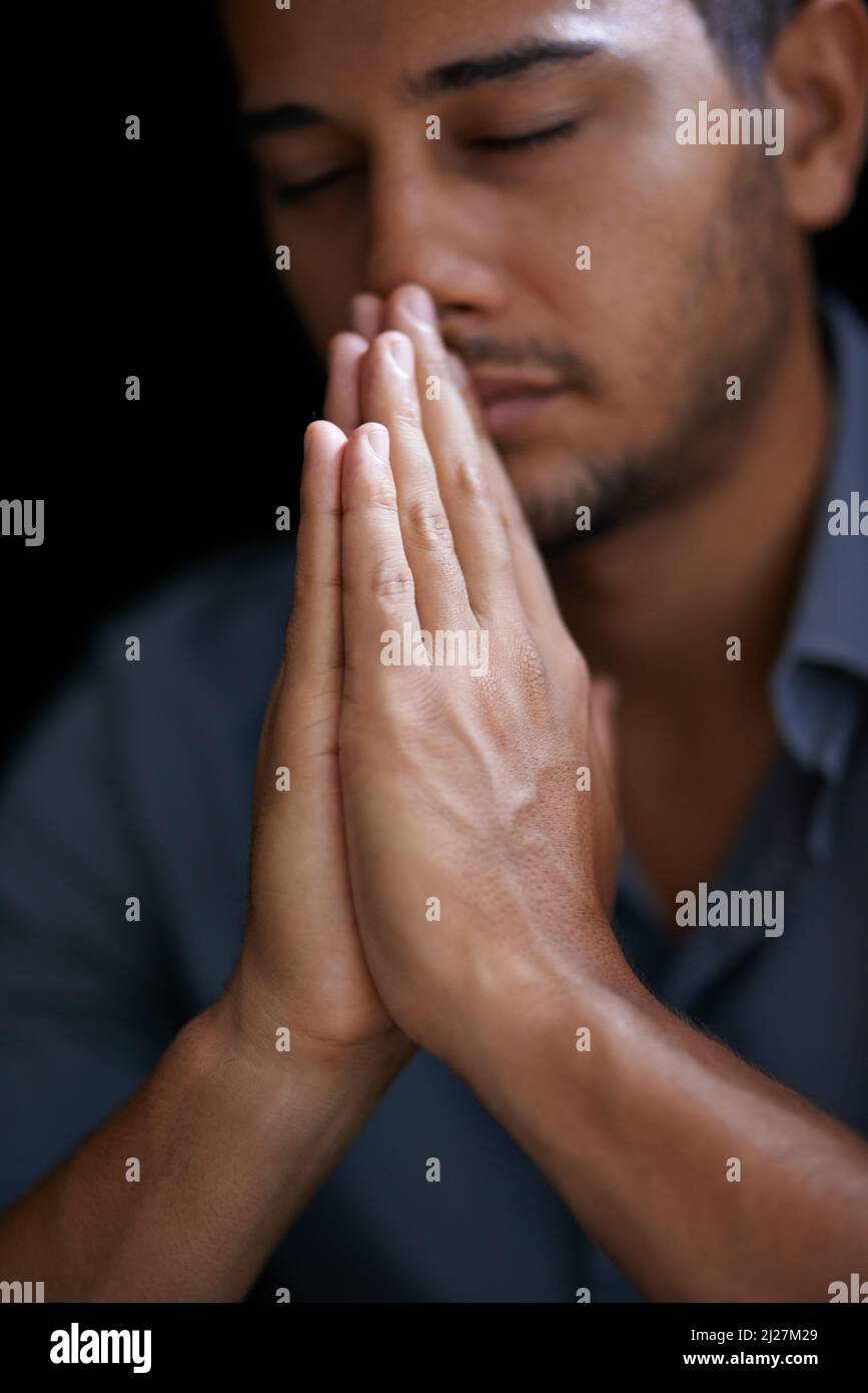 Praying for guidance and strength. Cropped shot of a young man holding ...