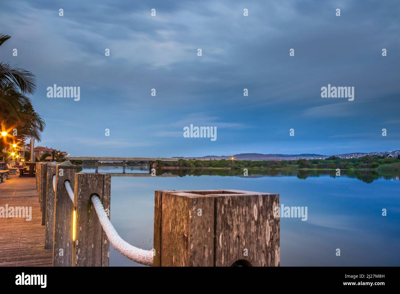 Overcast sunrise over Mossel bay lagoon from a boardwalk with bridge in ...