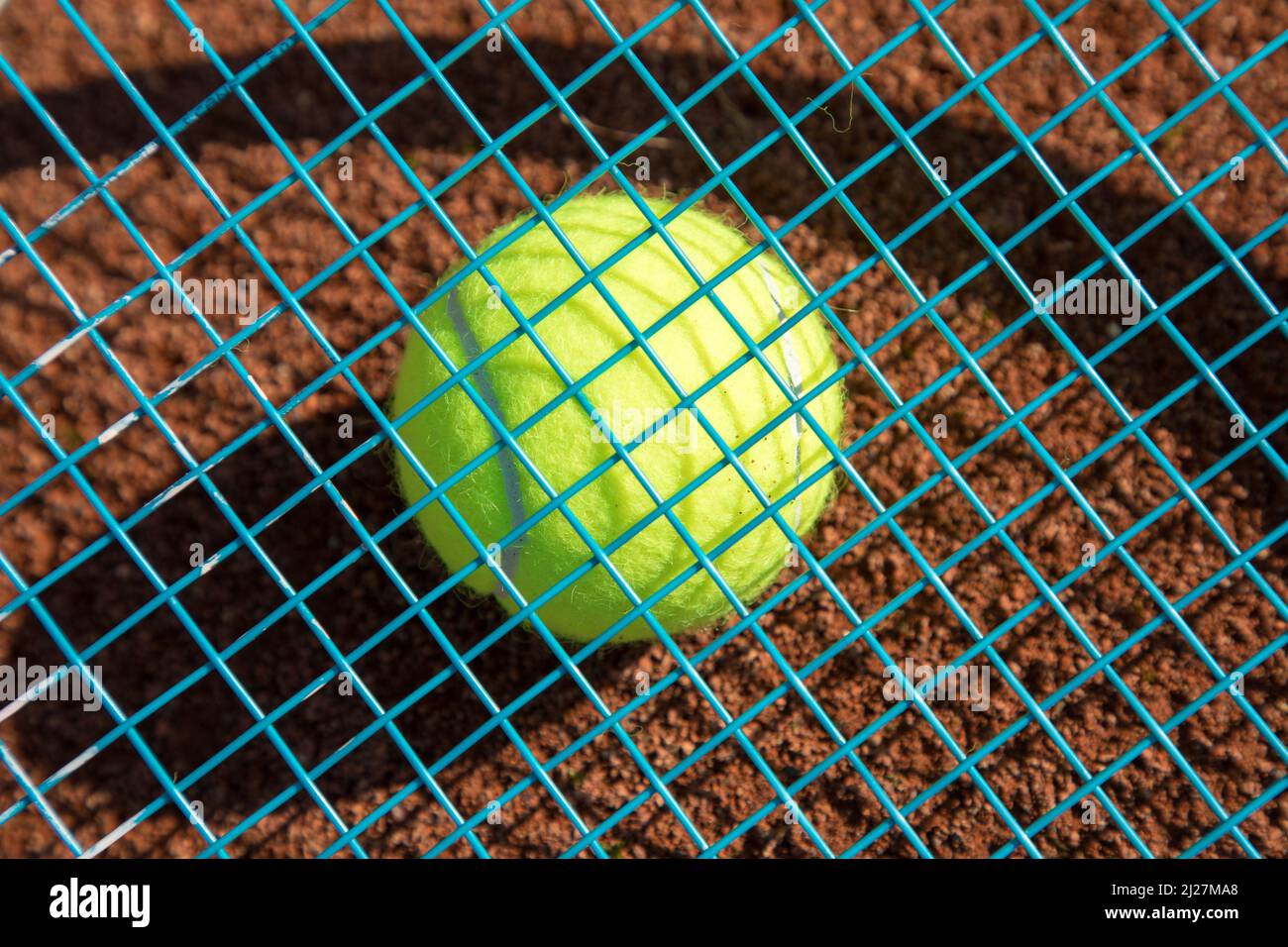 A closeup of the tennis ball on the court behind the tennis racquet net ...