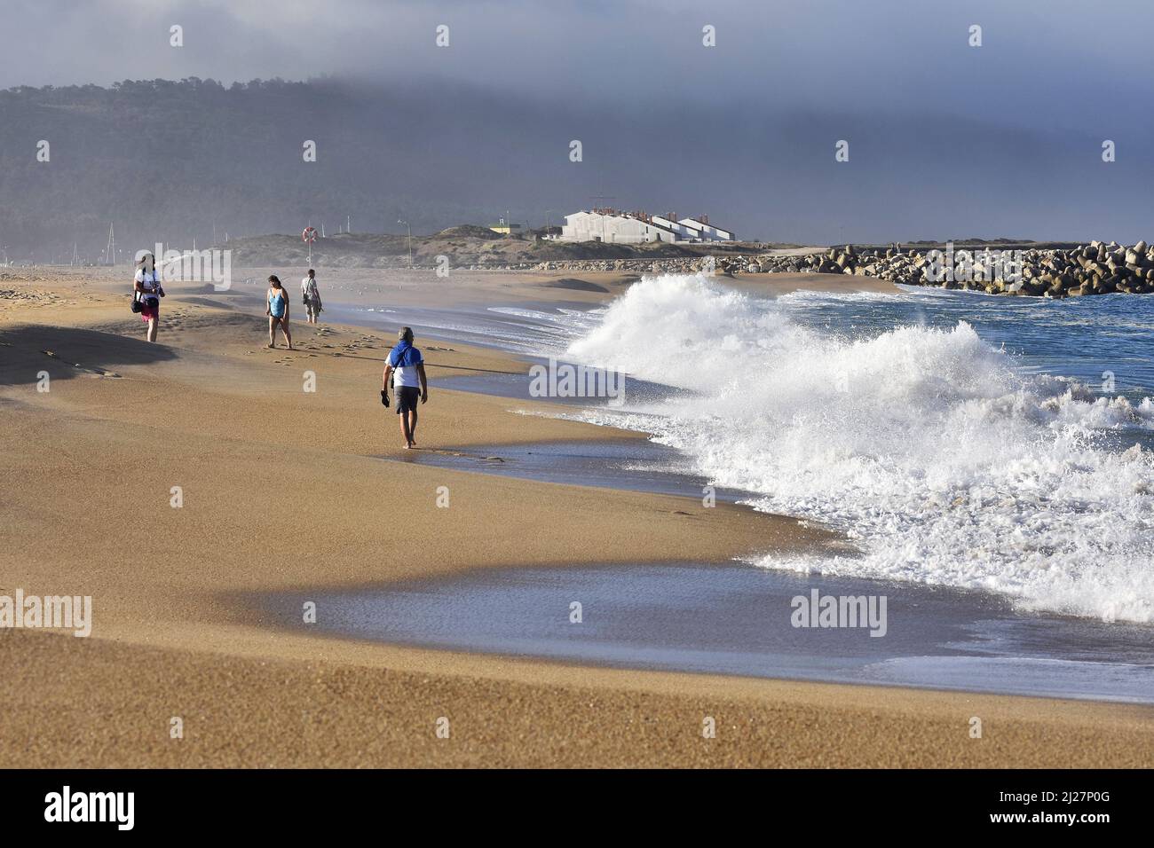 Praia da Nazare, people walking on the sandy beach in the morning ...