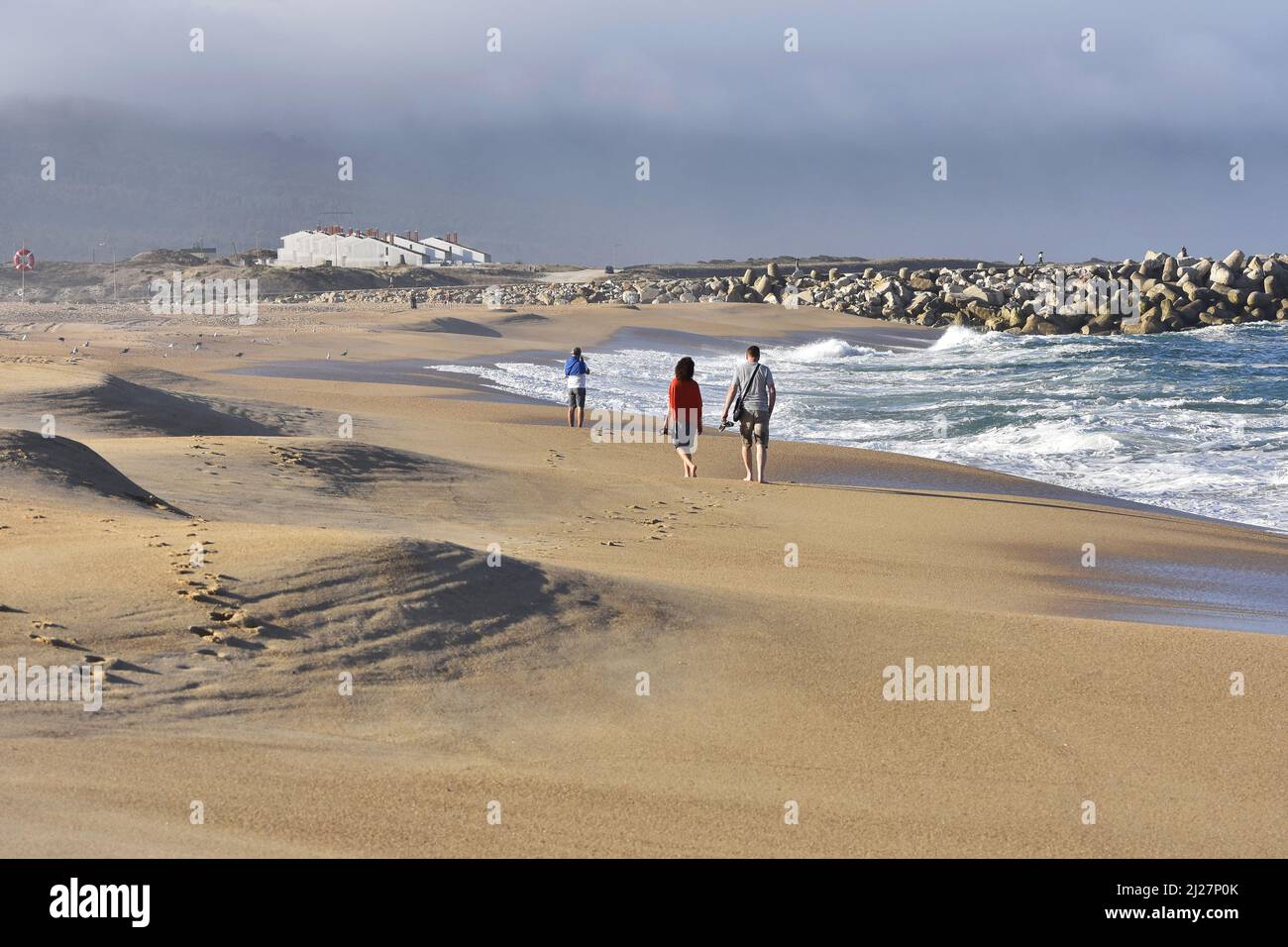 Praia da Nazare, people walking on the sandy beach in the morning ...
