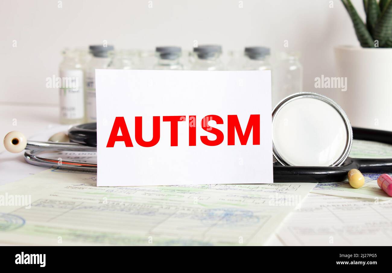 Autism word written on medical blue folder with patient files, pills ...