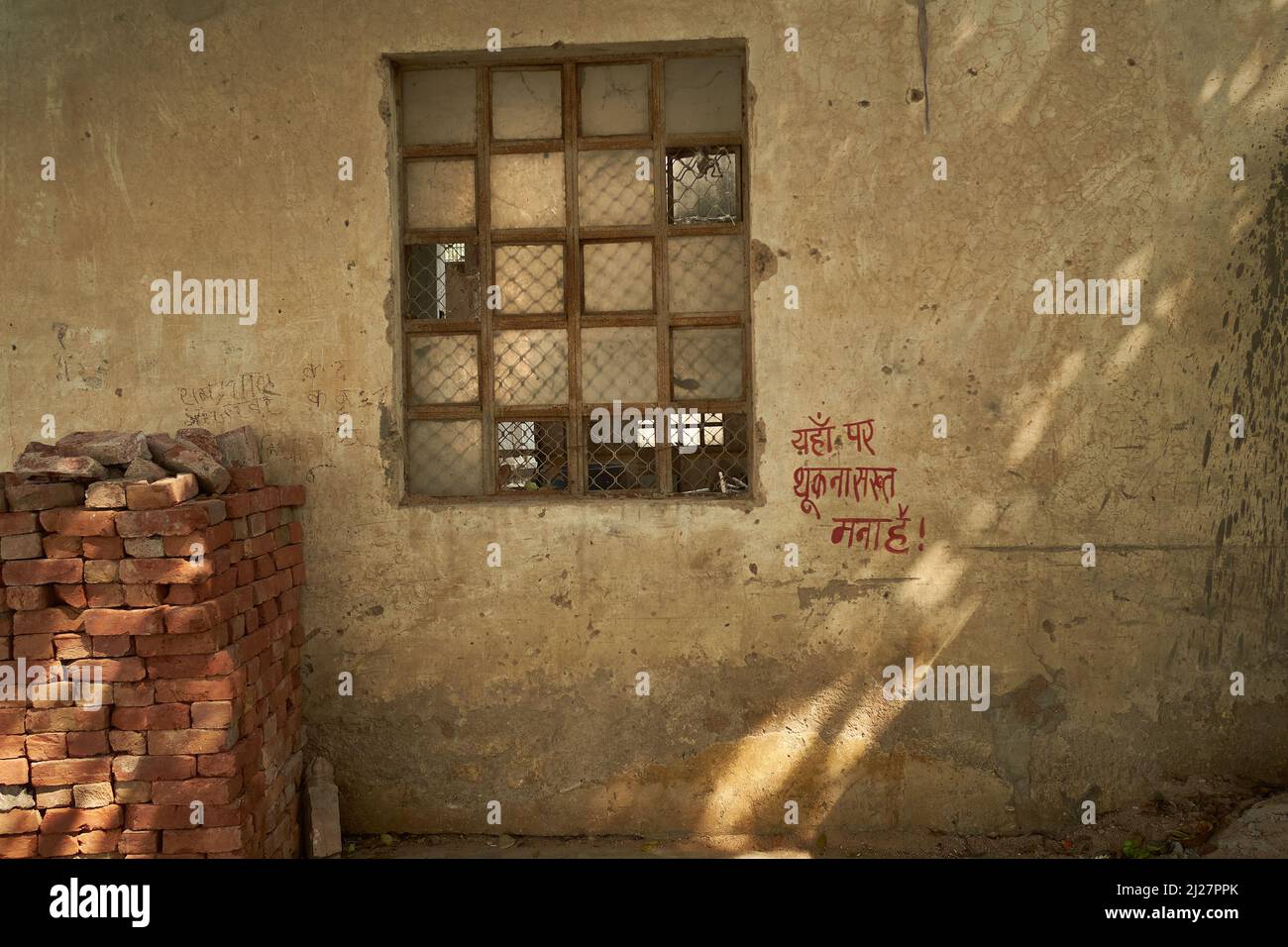 A pile of bricks lies next to an unmaintained house. The wall reads "do ...
