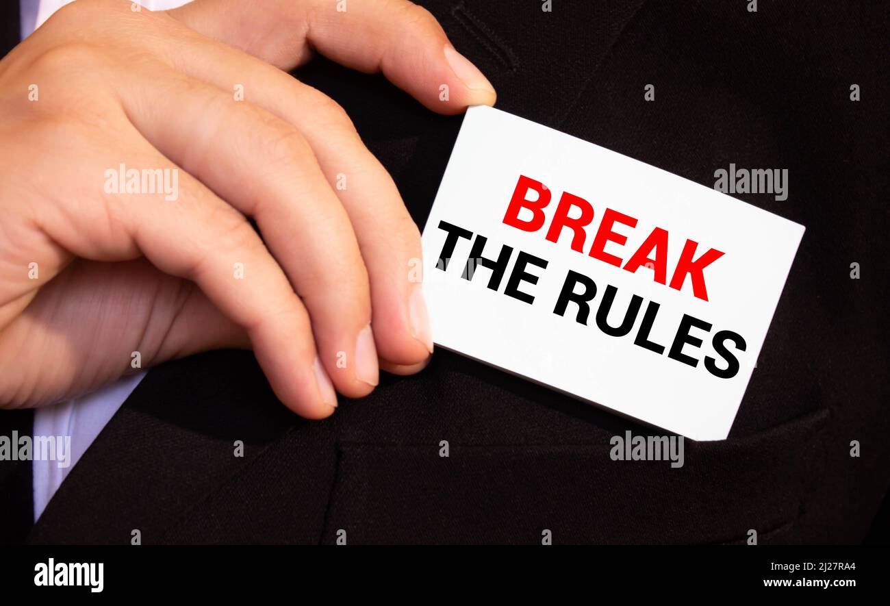 Businessman holding a card with text BREAK THE RULES. Keyboard, diagram ...
