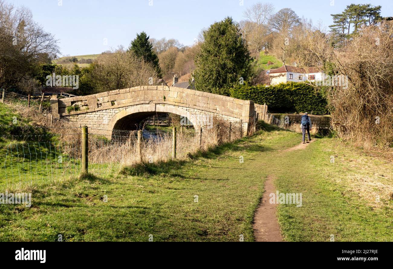 Walker on the Limestone Link National Trail passing a bridge on the ...
