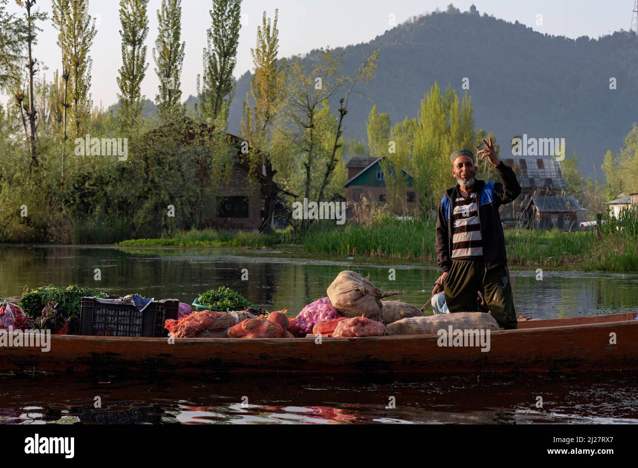 A vegetable seller gestures from his boat as he sell vegetables during ...