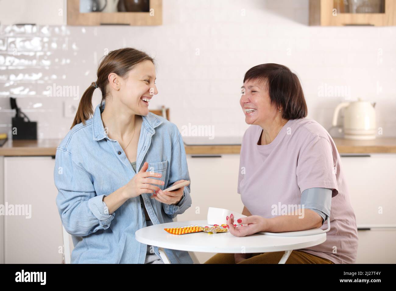 Happy young female providing medical care, helping to support an senior ...