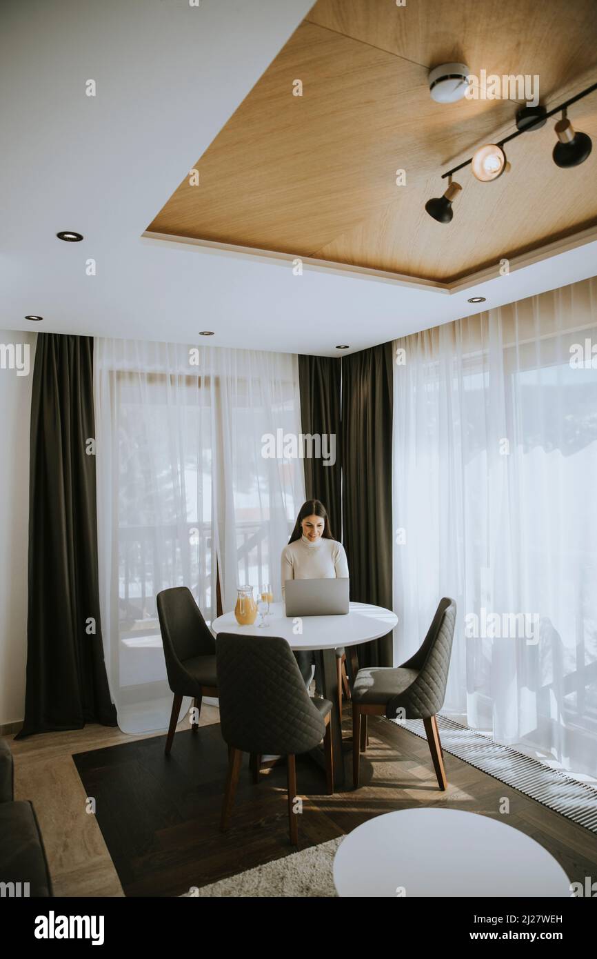 Young woman using a laptop computer and drinking healthy orange juice ...