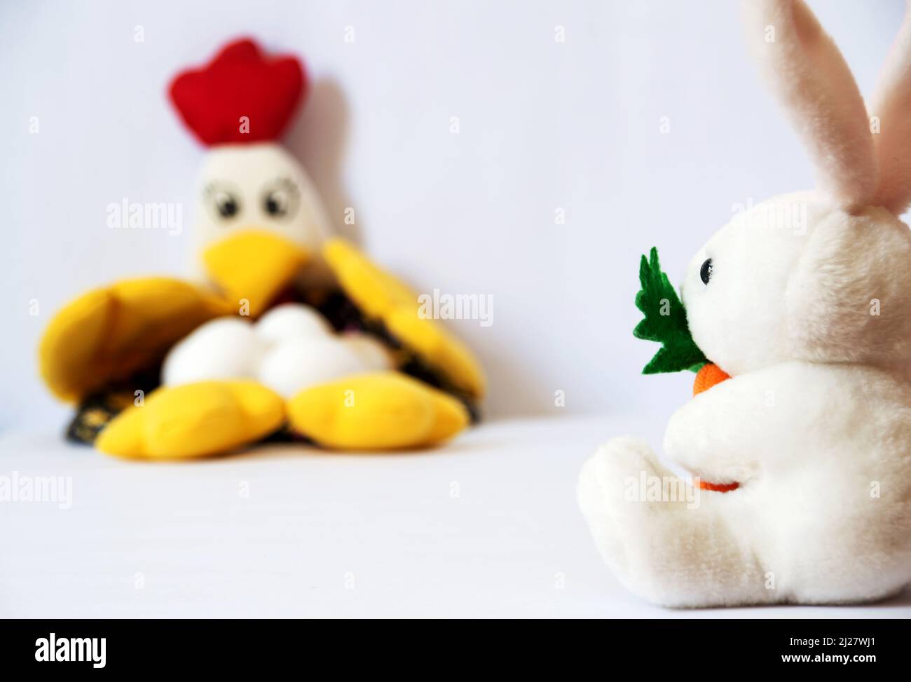 White plush bunny on the right side of the image and hen hugging eggs ...