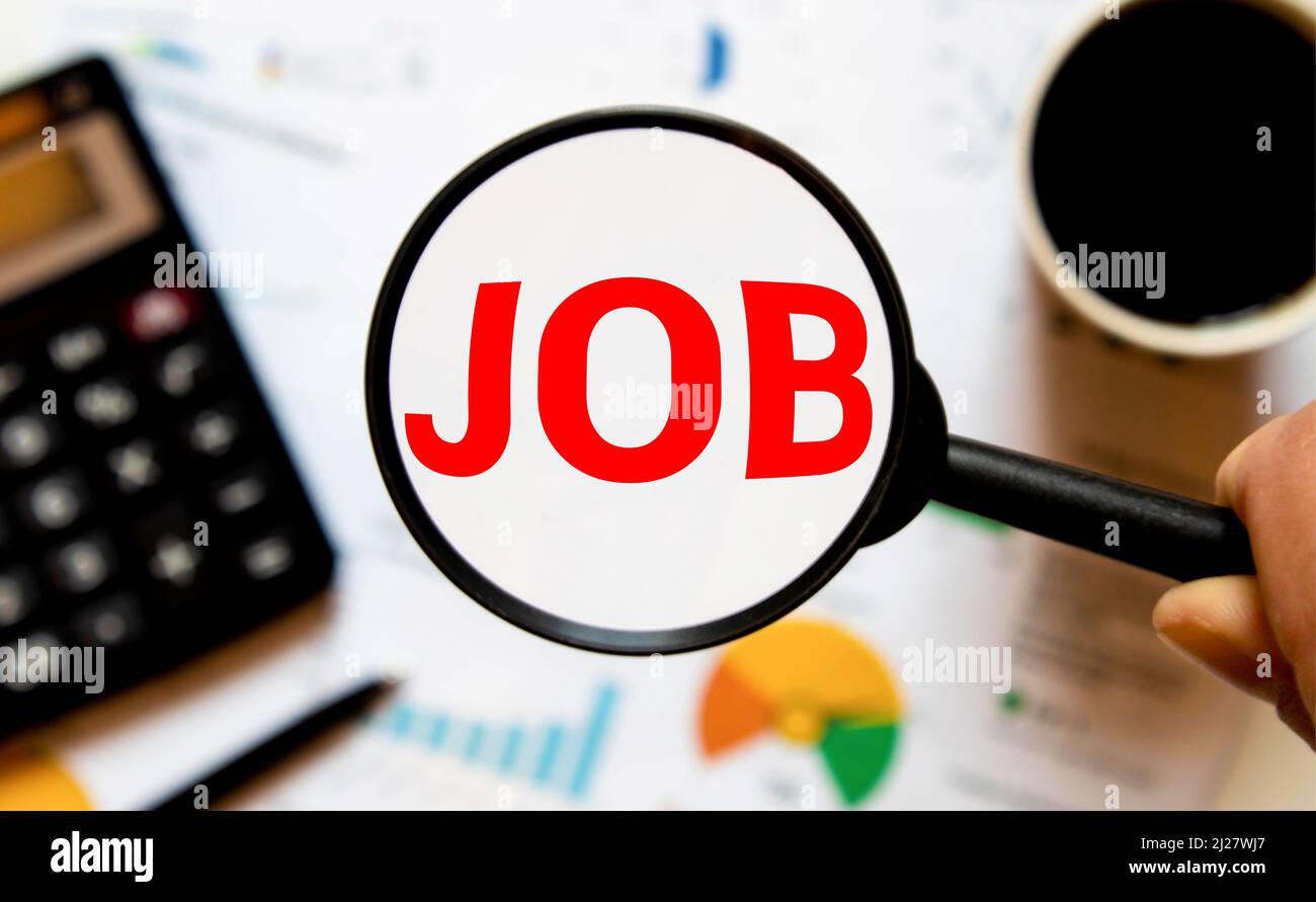 magnifying glass with text JOB on wooden table and green background ...