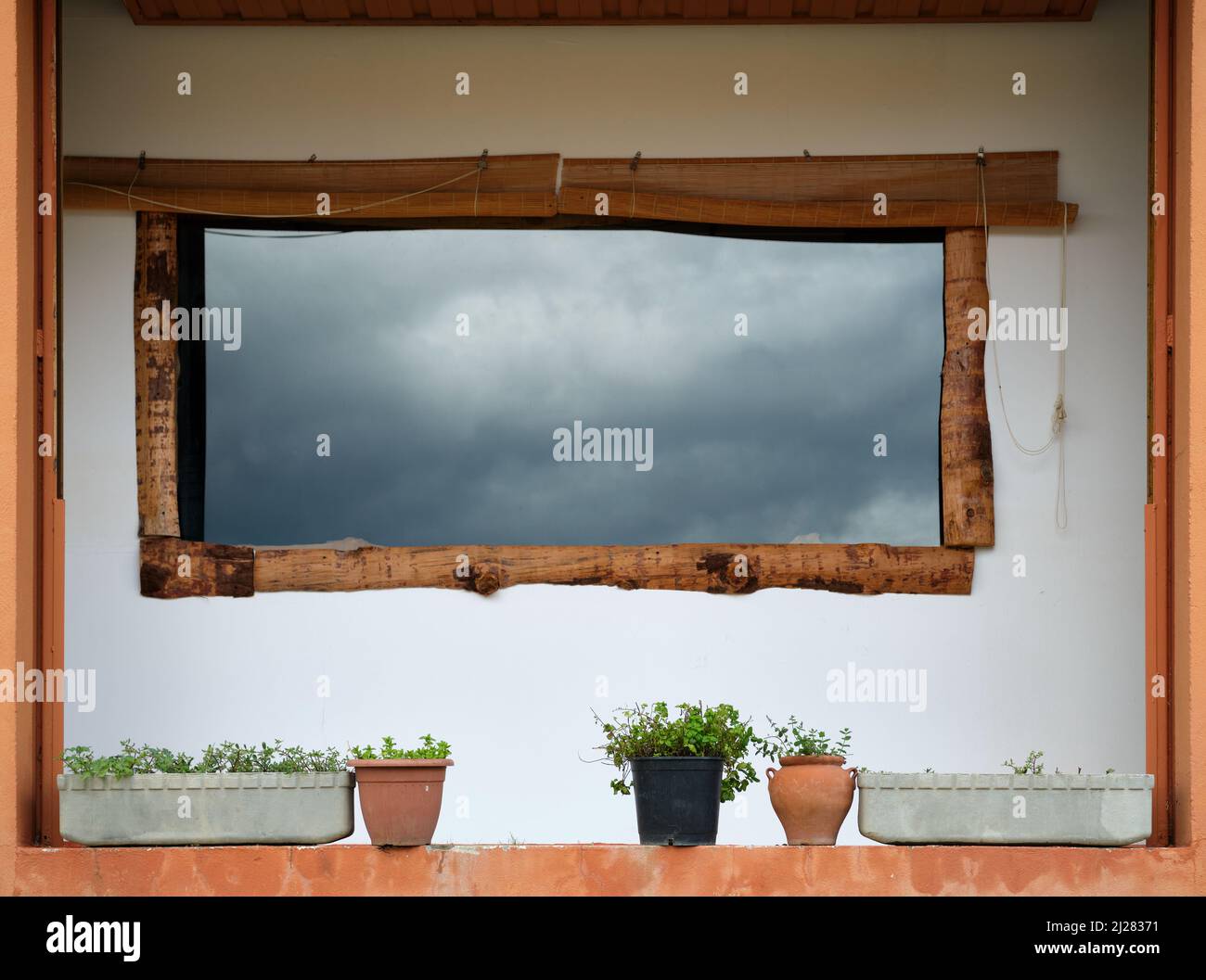 Glass window with wooden frame with plant pots.Reflection of clouds on ...