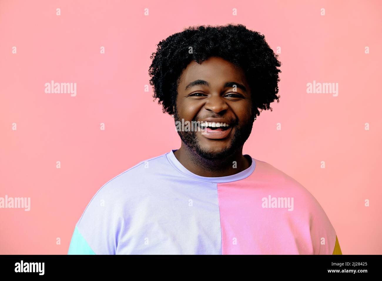 young happy african american man posing in the studio over pink ...