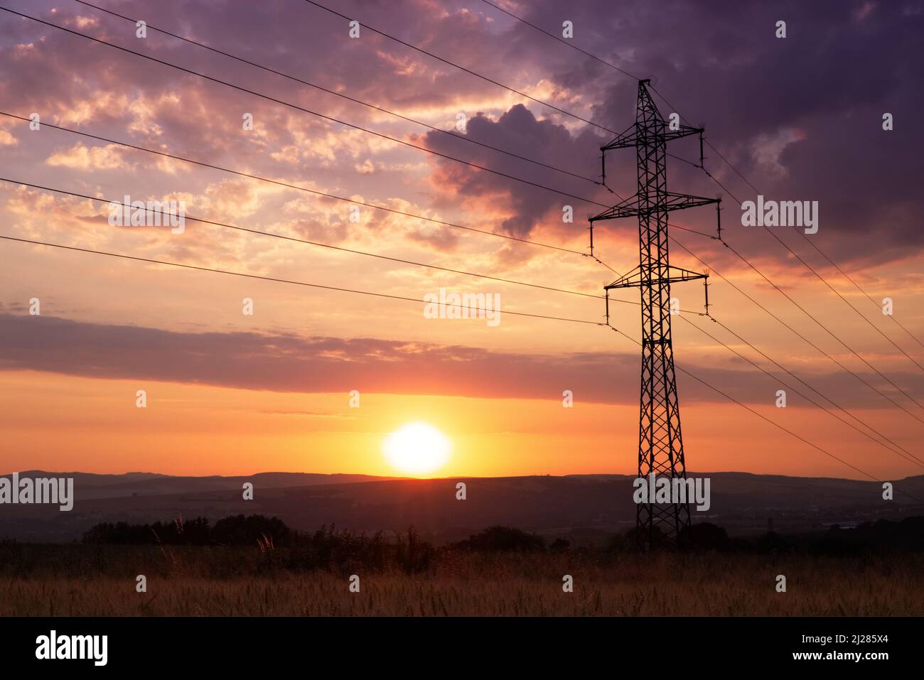 Sunset behind electricity pylon. Dramatic sky and electric power lines ...