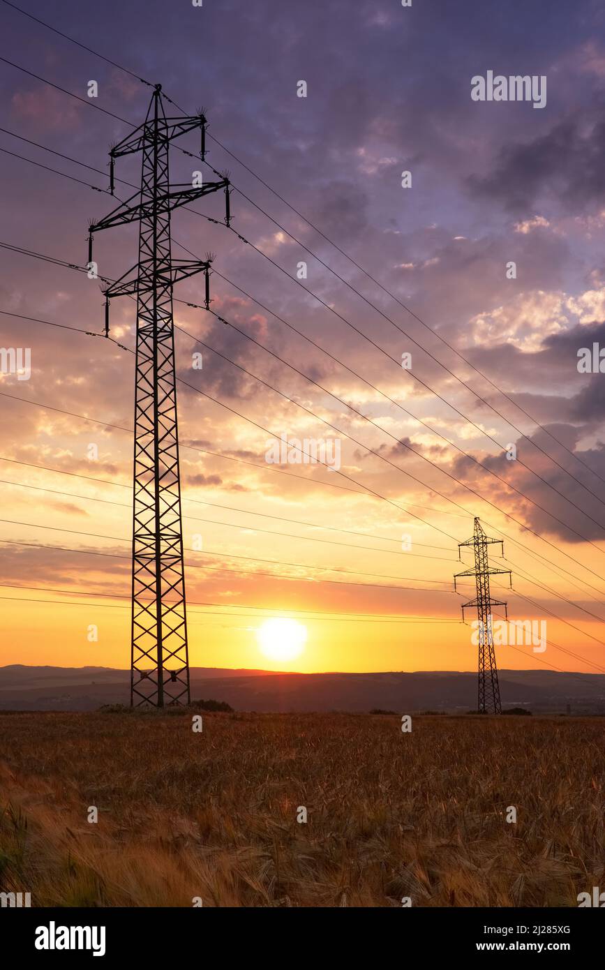 Sunset behind electricity pylons. Dramatic sky and electric power lines ...