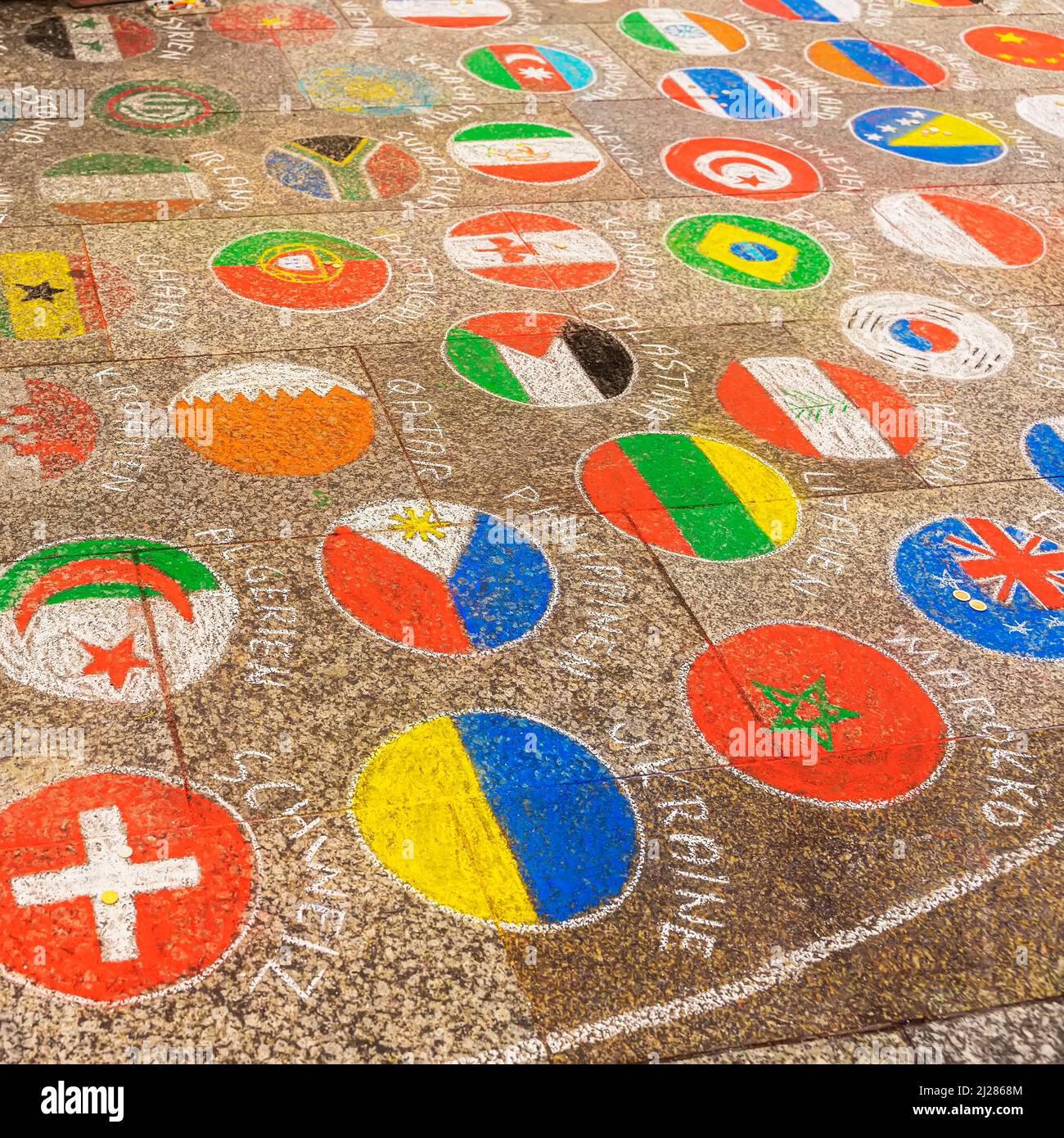 Colorful emblems, flags of different countries painted on pavement with ...