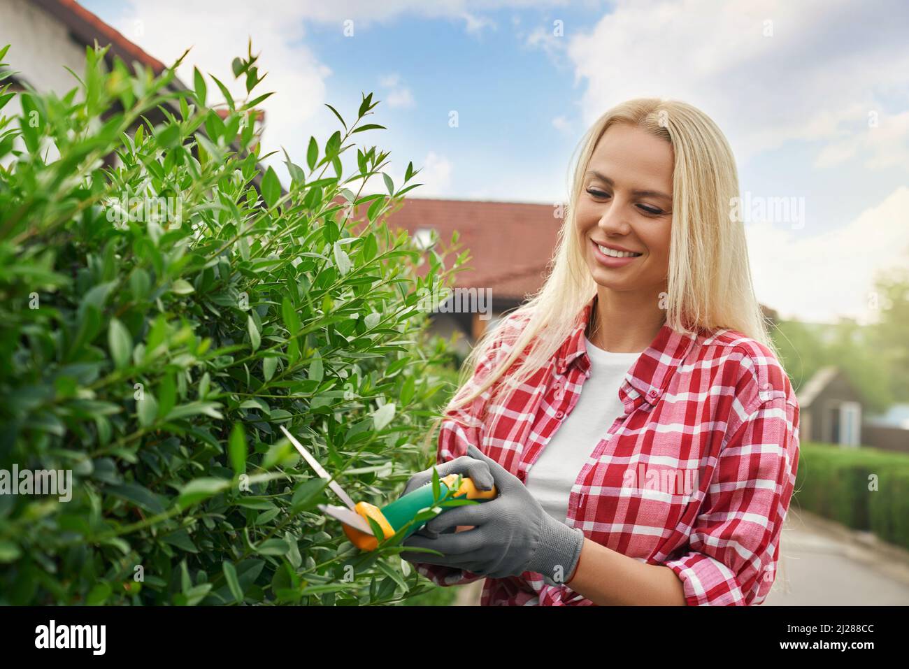 Positive caucasian woman with blond hair using gardening scissors for ...