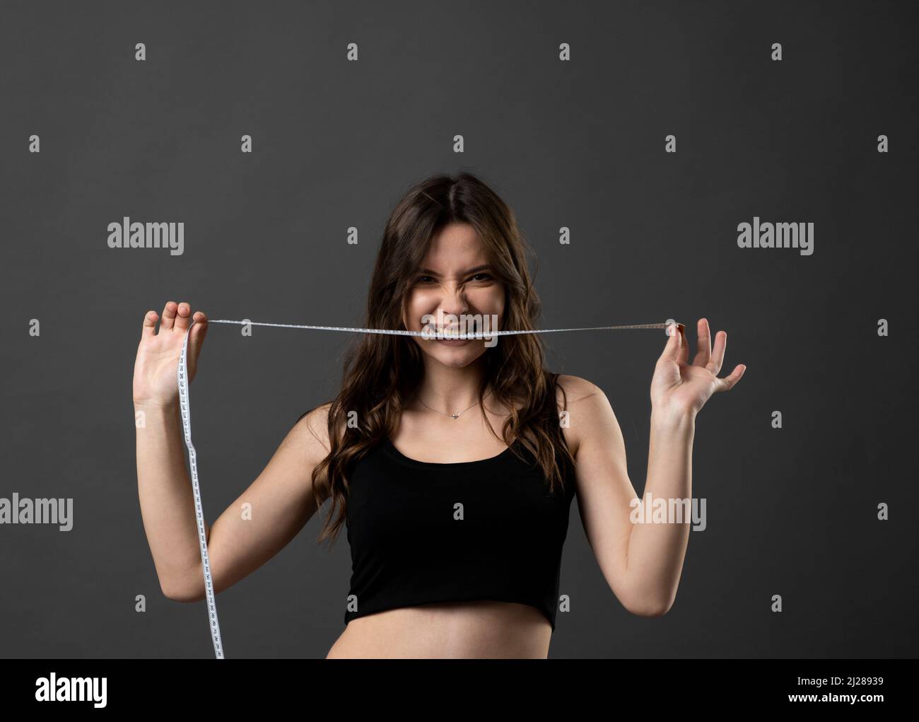 Beautiful sporty fitness woman in a black top with a white measuring ...