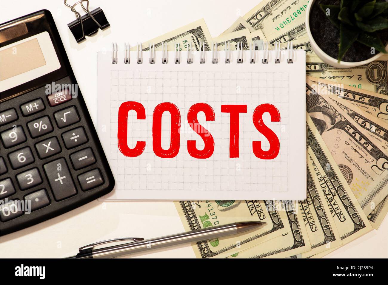 The word COSTS is written on notepad on desktop with laptop Stock Photo ...