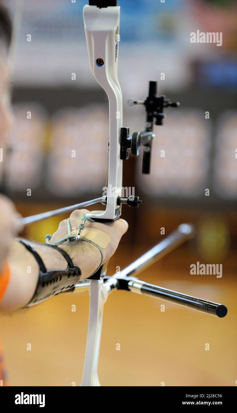 A vertical shallow focus shot of an archer with bow takes aim at a ...