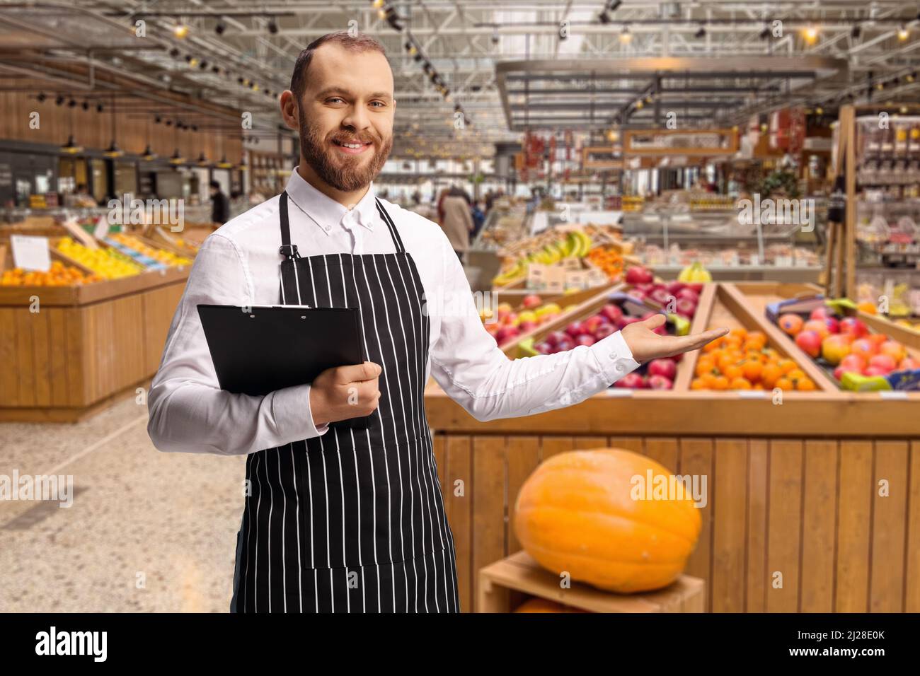 Male shop assistant in a grocery store welcoming customers Stock Photo ...