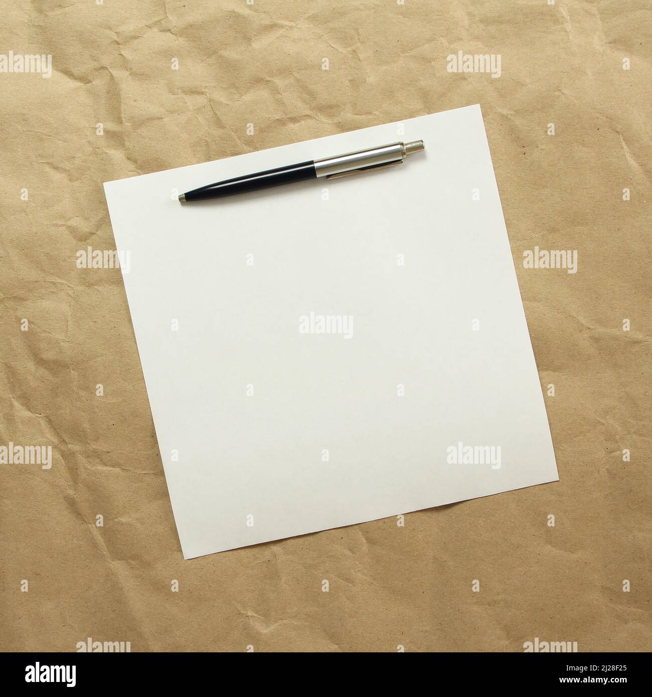 Square white empty sheet of paper with pen on a beige craft paper ...