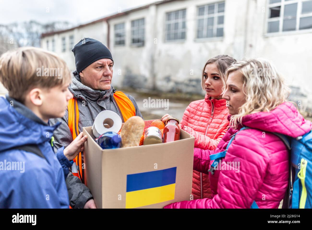 Male NGO worker gives a box of basic food and toiletries to a family of ...