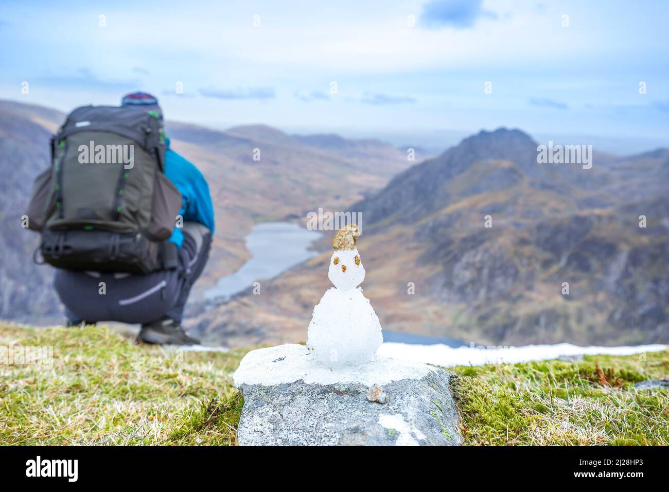 Rear view of male hiker & funny mini snowman on top of Y Garn mountain ...