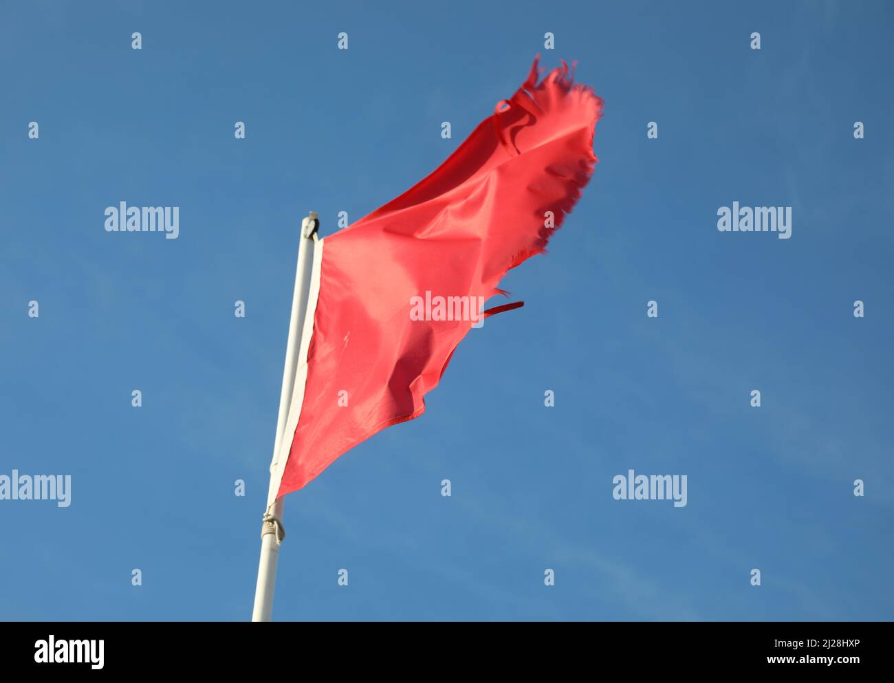 Wide Red flag symbol of danger and blue sky in background Stock Photo ...