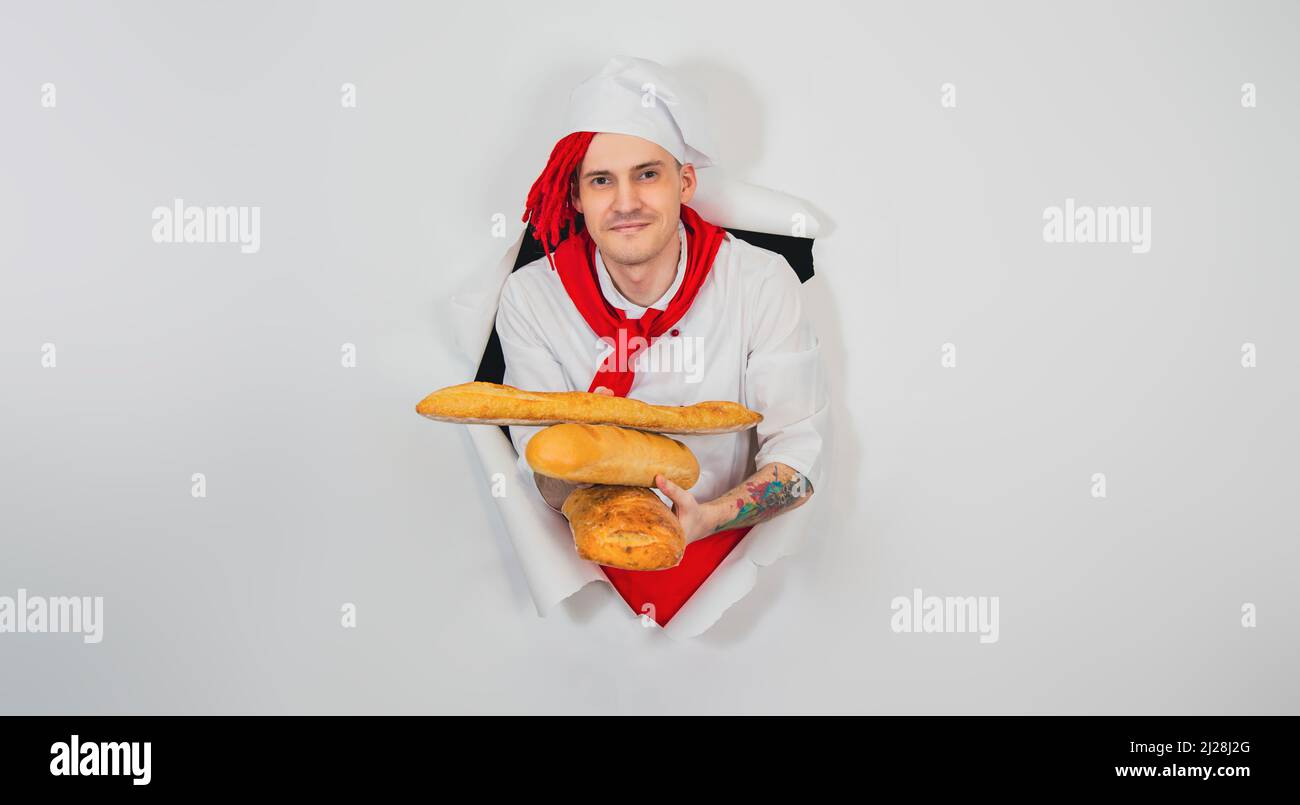 Young man with red dreadlocks dressed as chef holding white bread. Male ...