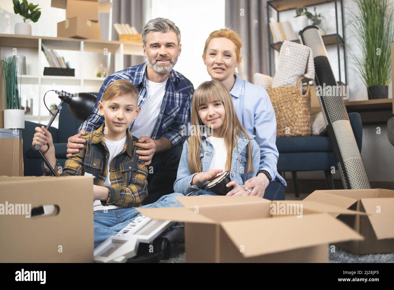 Cheerful Caucasian parents and two happy children sitting together on ...