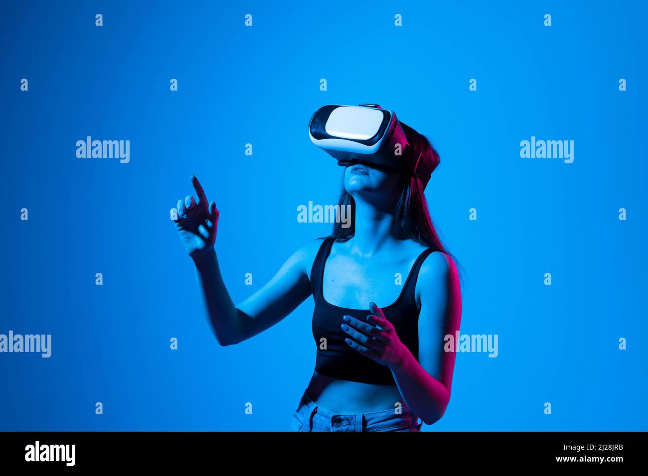 Close up of young woman stands in studio wearing VR glasses and swiping ...