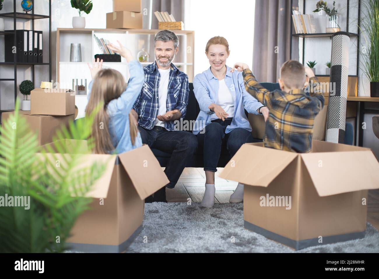 Two funny kids sitting inside cardboard box and smiling while their ...