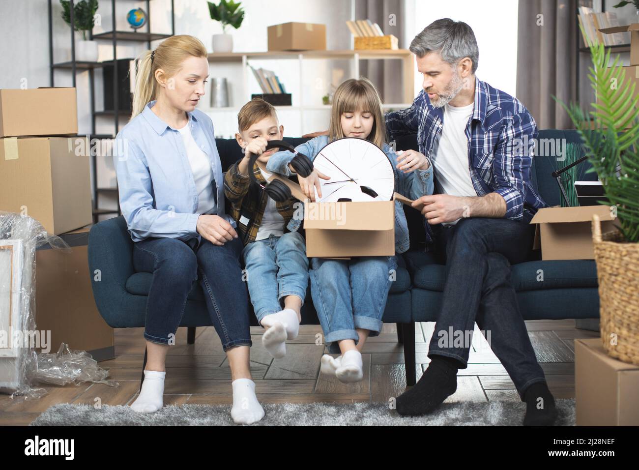 Two cute kids, boy and girl helping their Caucasian parents packing ...