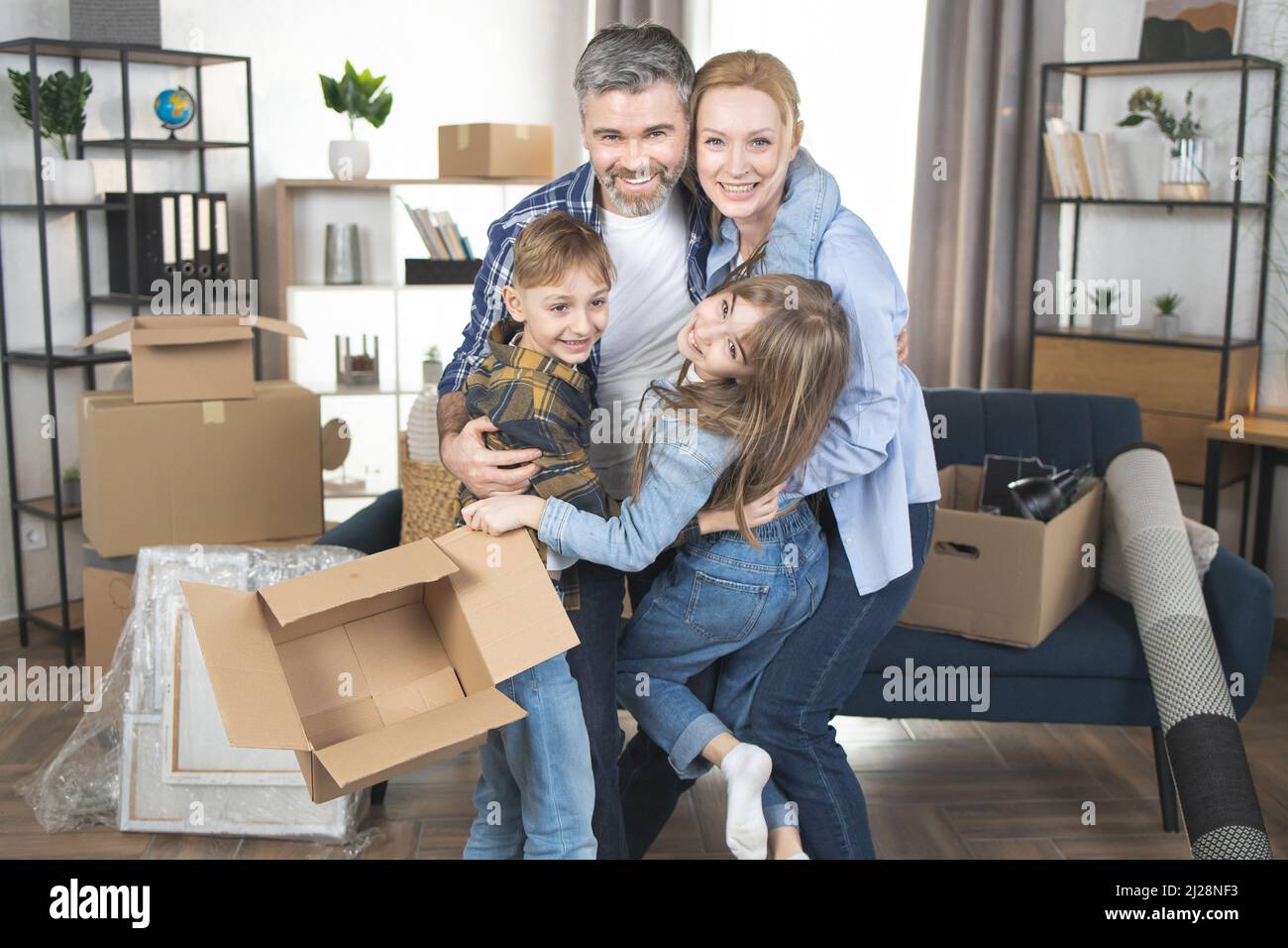 Happy Caucasian man and woman having fun with two kids at new house ...