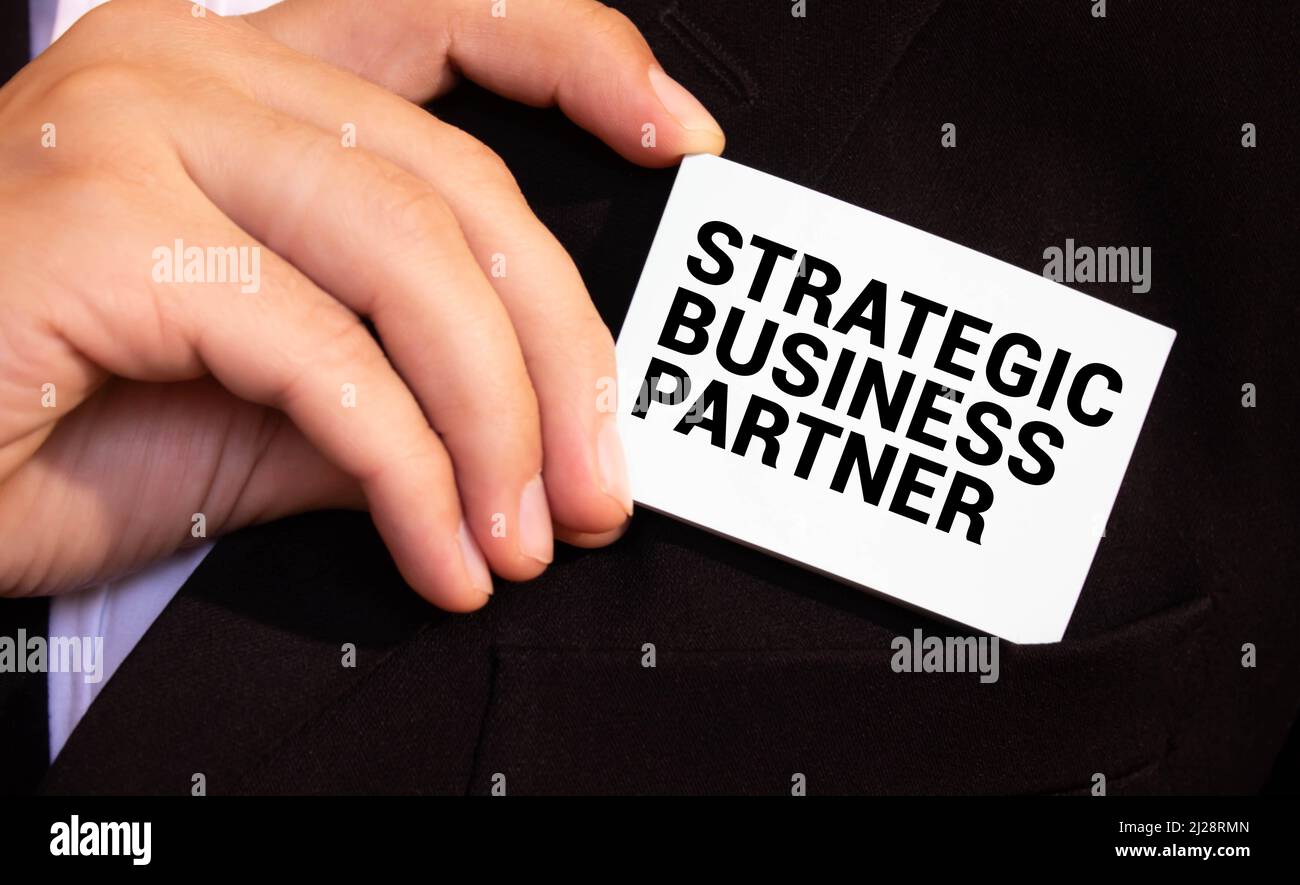 Closeup on businessman holding a card with STRATEGIC BUSINESS PARTNER ...