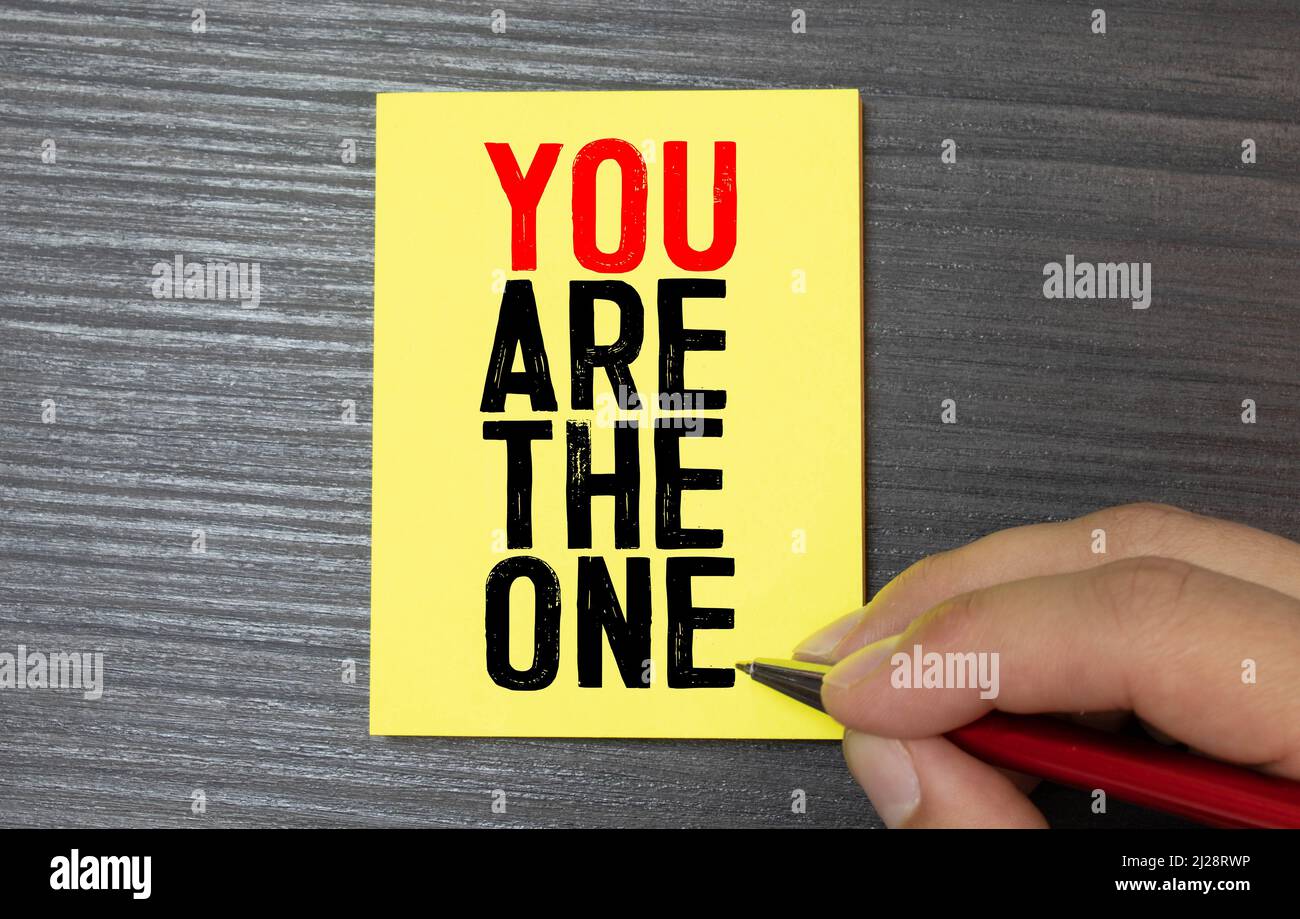 A man is holding a piece of paper which is saying 'You are the one ...