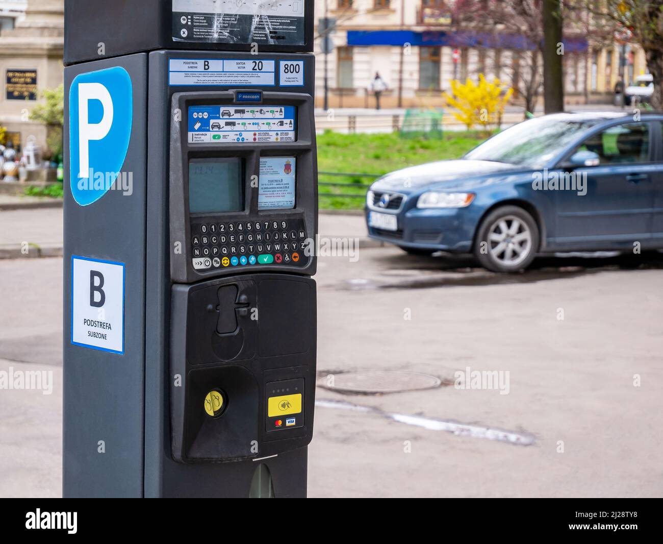 Parking meter ticket machine on the street and a car nearby, outdoors ...