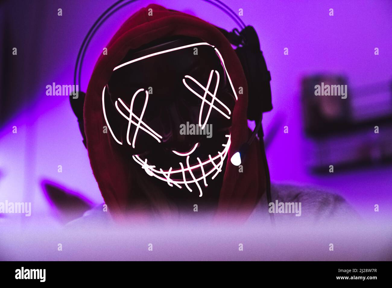Masked hacker concept. Identity and data protection. Headphones and red ...