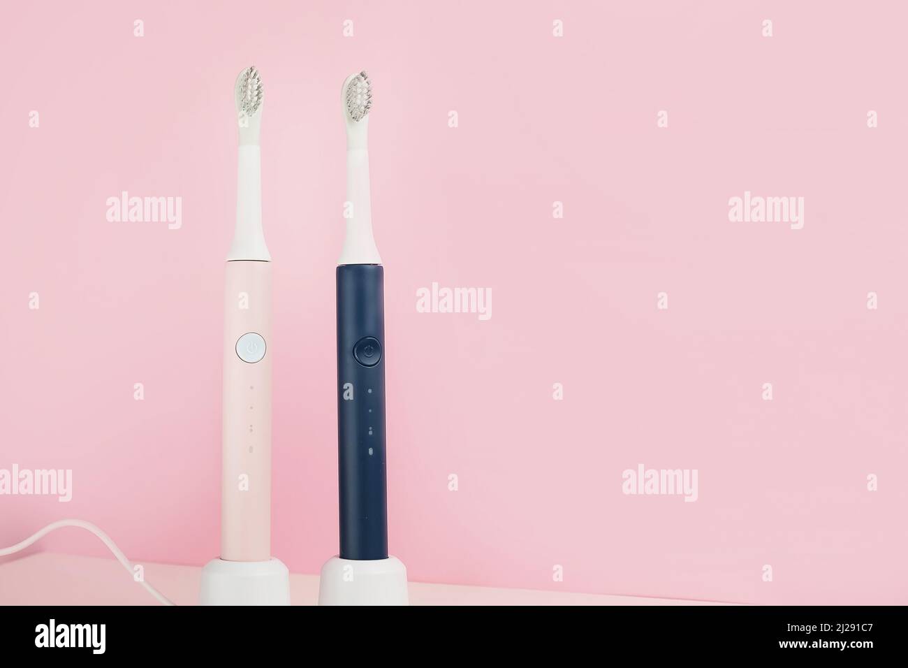Two new modern ultrasonic toothbrushes. Dental care supplies on pink ...