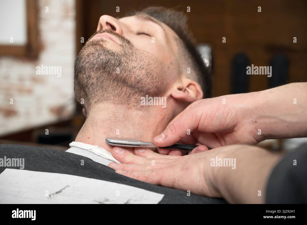 Barber shaving bearded male with a sharp razor. High quality ...