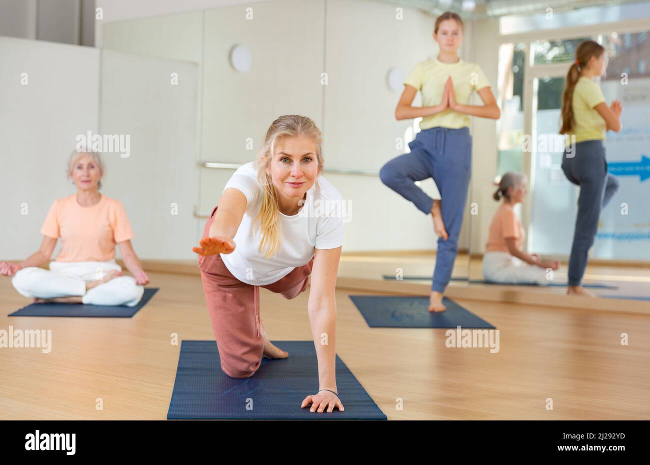 Family of three generations exercising Hatha yoga poses in yoga studio ...