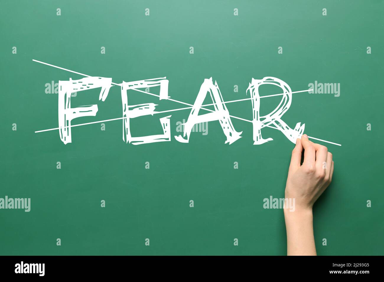 Woman crossing out word FEAR written on chalkboard. Fight your fears ...
