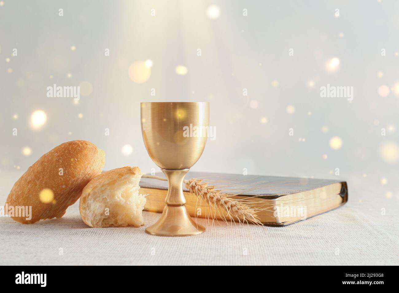 Chalice of wine with bread and Bible on light background. Holy ...