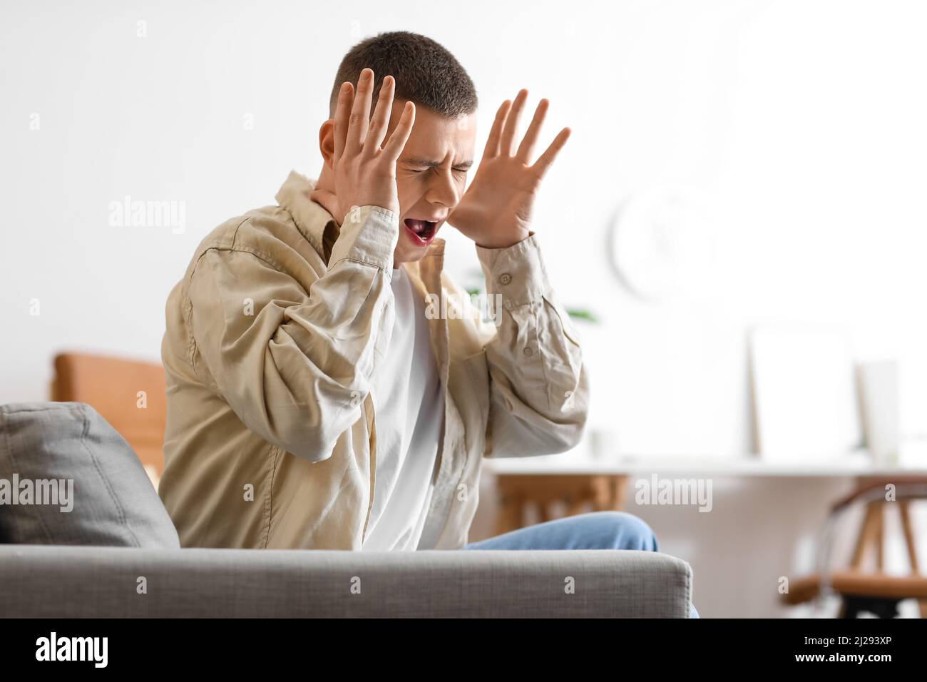 Nervous young man sitting on sofa at home Stock Photo - Alamy