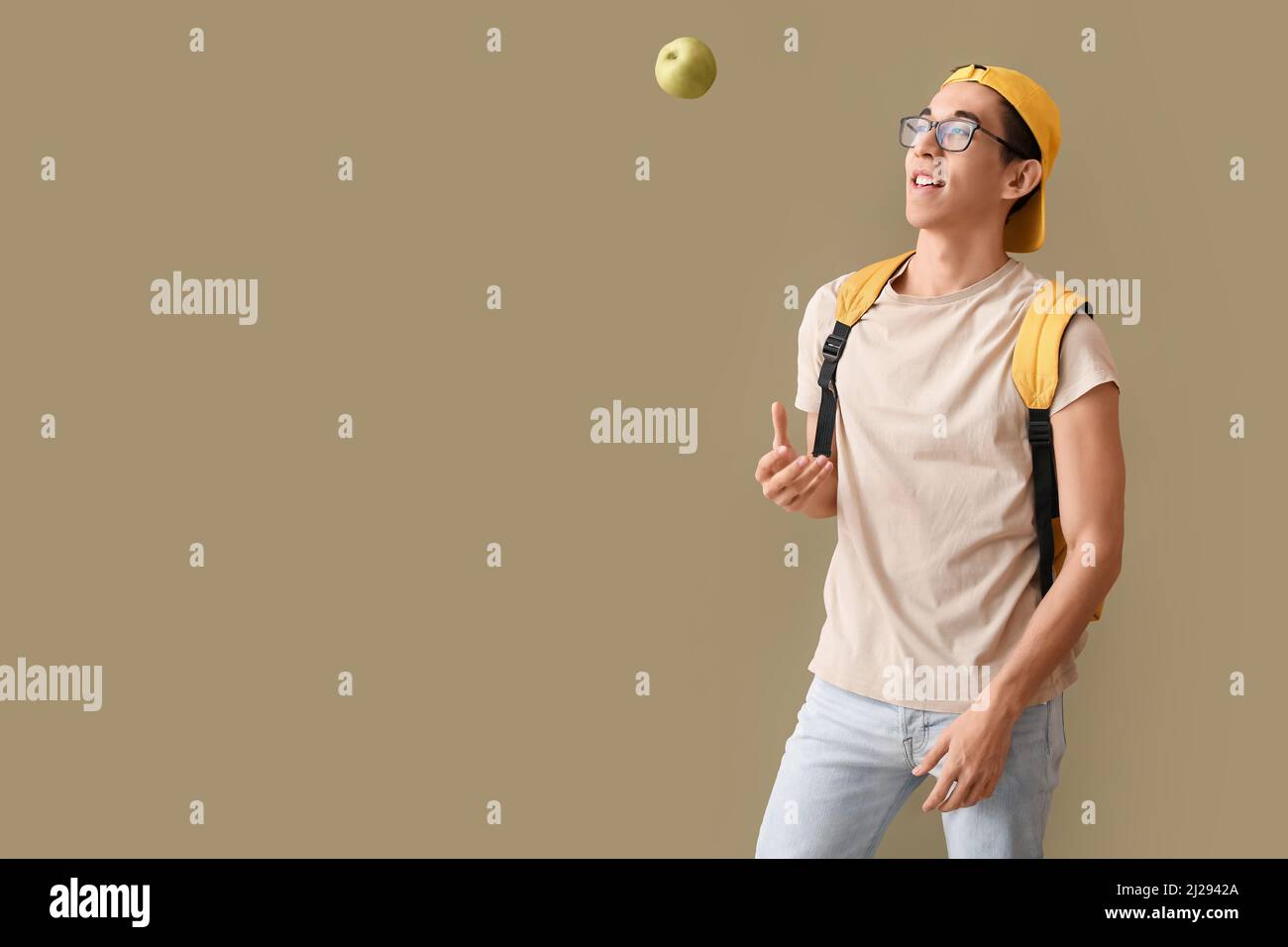 Male Asian student throwing apple on color background Stock Photo - Alamy