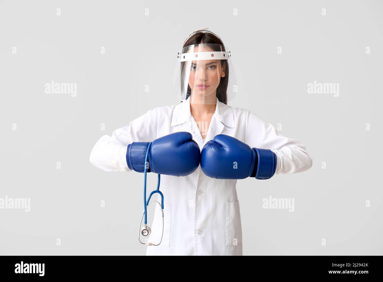 Young female doctor with boxing gloves and stethoscope on light ...