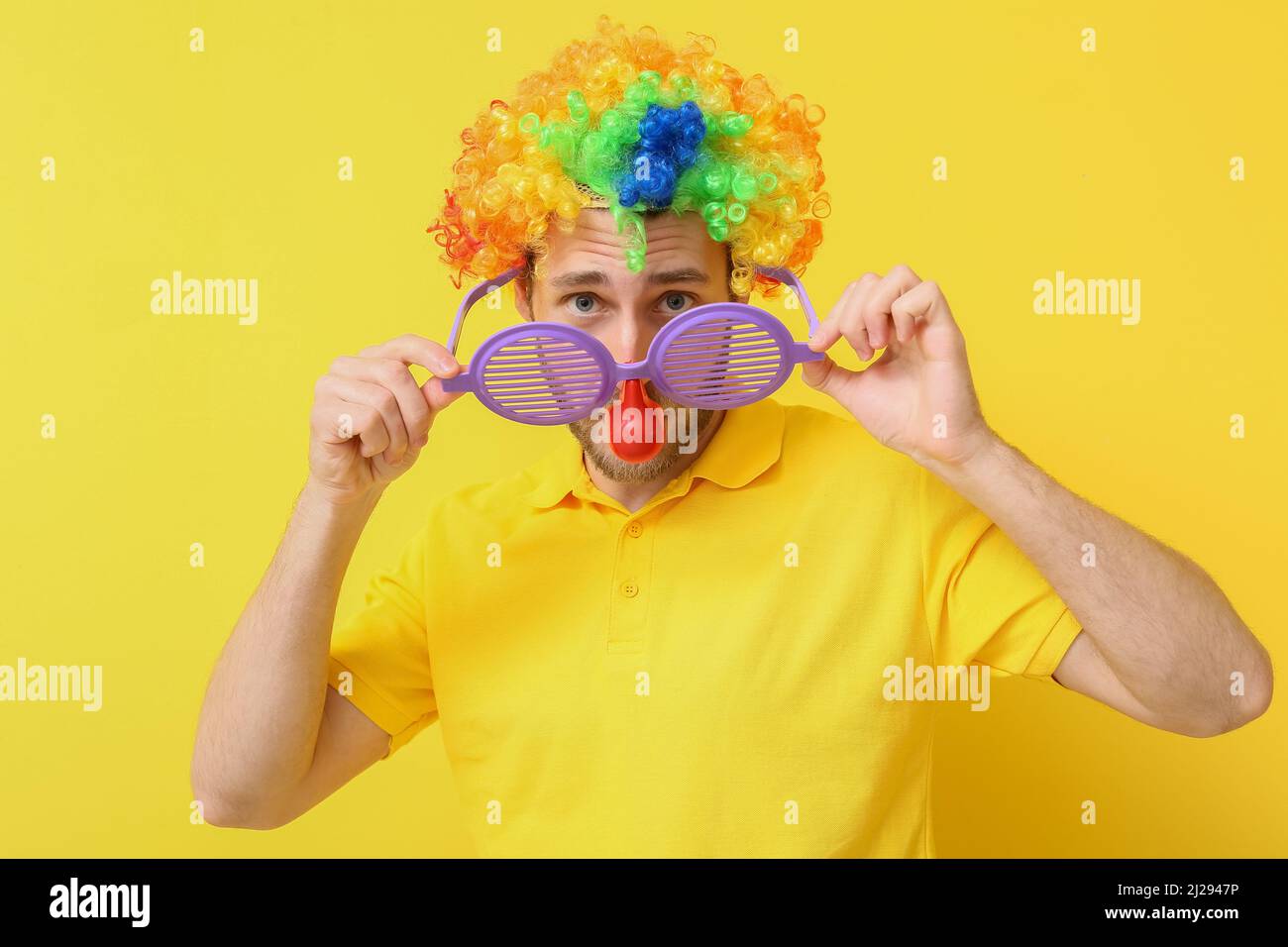 Funny young man in disguise on yellow background. April fools' day ...