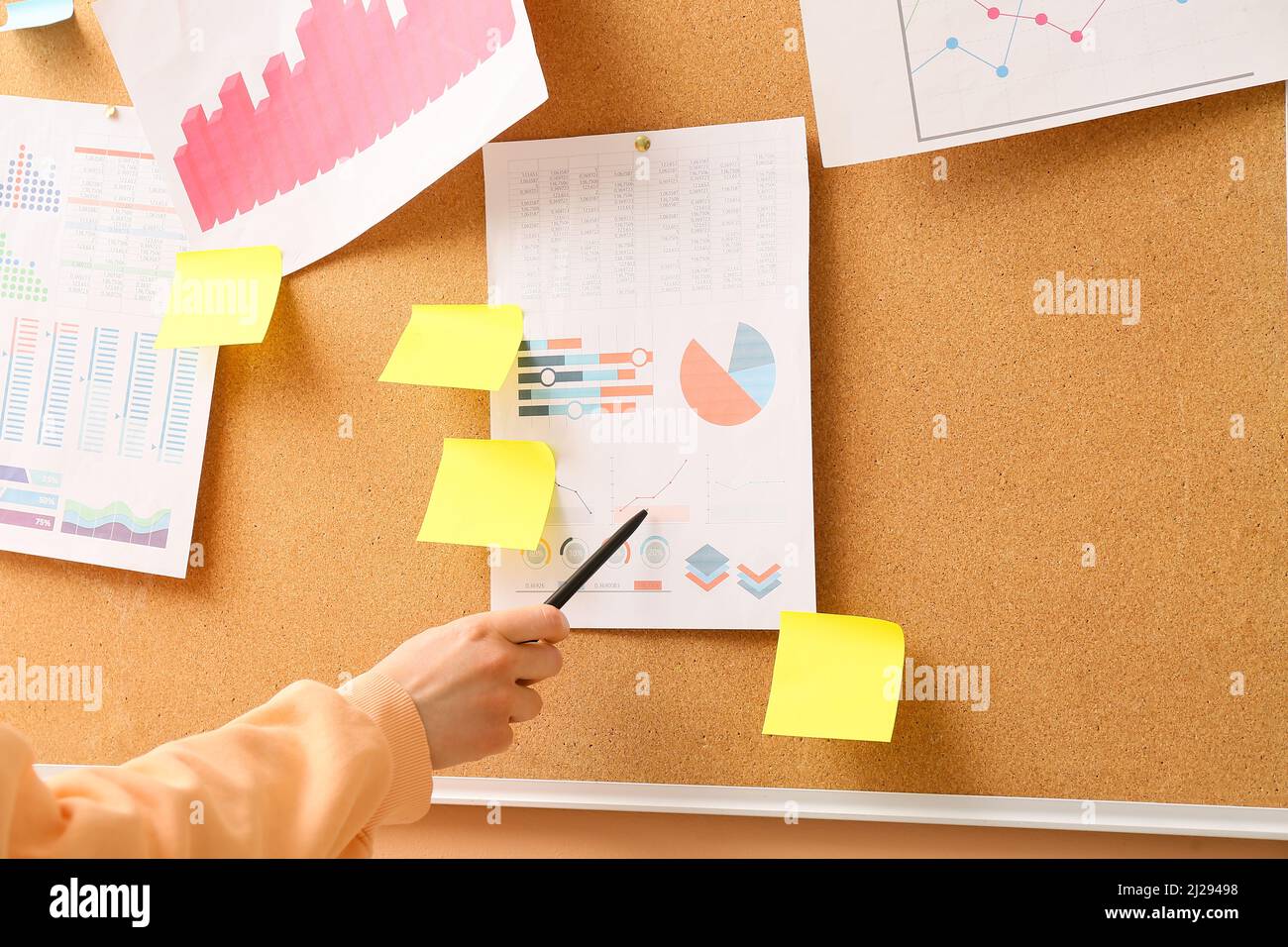 Woman pointing at charts on board with sticky notes Stock Photo - Alamy