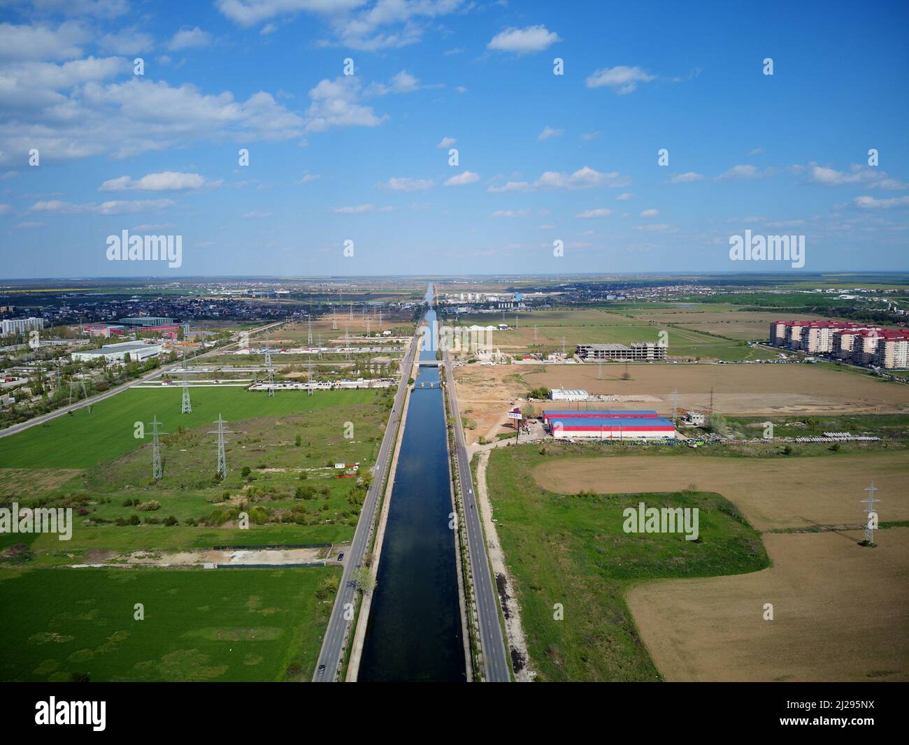 A river in between landscape fields with electrical pylons Stock Photo ...
